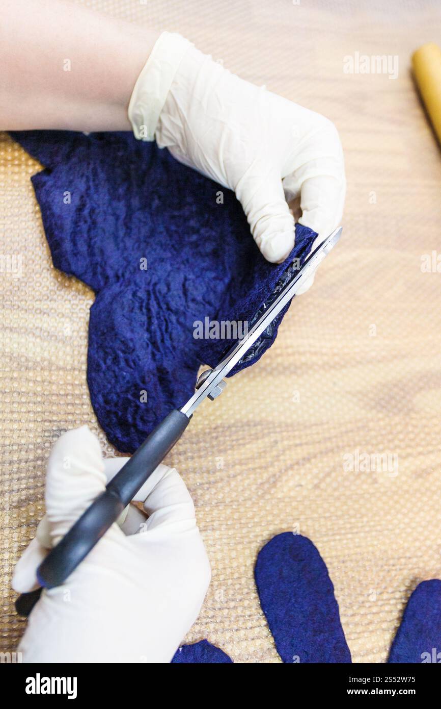 workshop of hand making a fleece gloves from blue Merino sheep wool ...