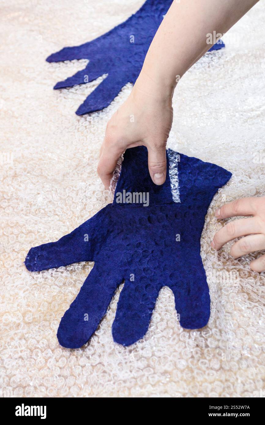 workshop of hand making a fleece gloves from blue Merino sheep wool ...