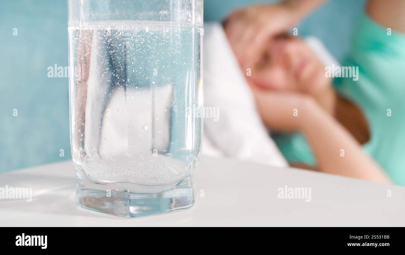 Glass of water with air bubbles from dissolving aspirin against woman ...