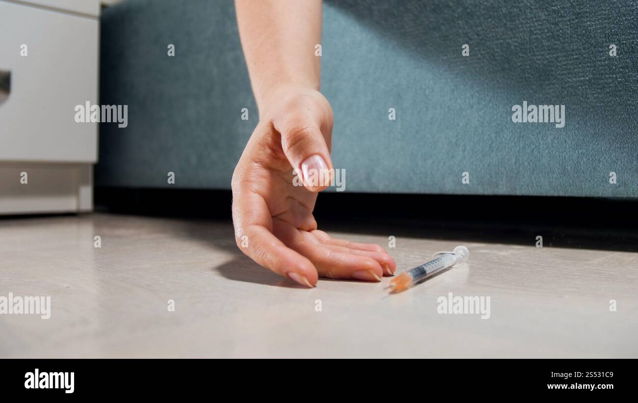 Closeup photo of empty syringe falling from female hand lying on floor ...
