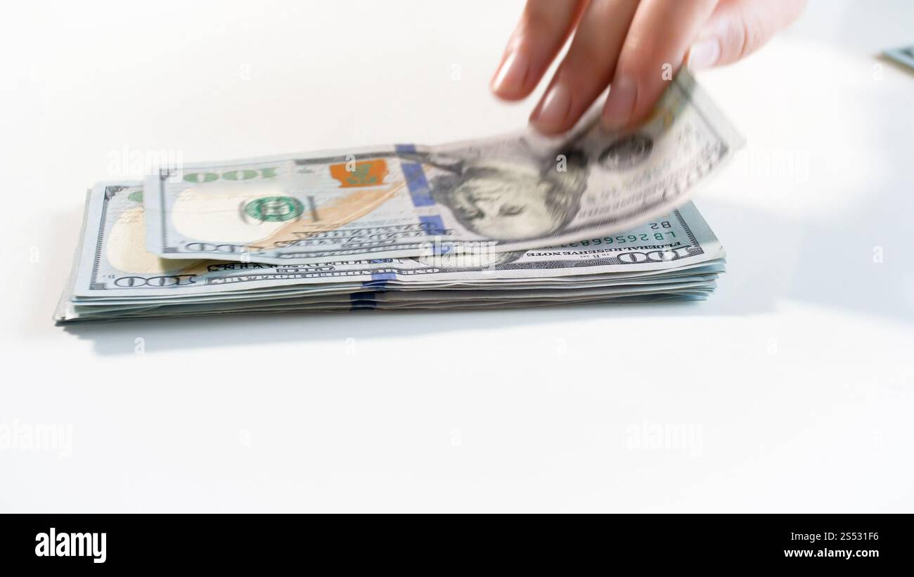 Closeup image of hand grabbing 100 dollars from big stack of money on ...