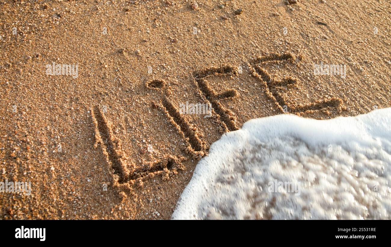 Closeup image of sea waves rolling over word life written on beach sand ...