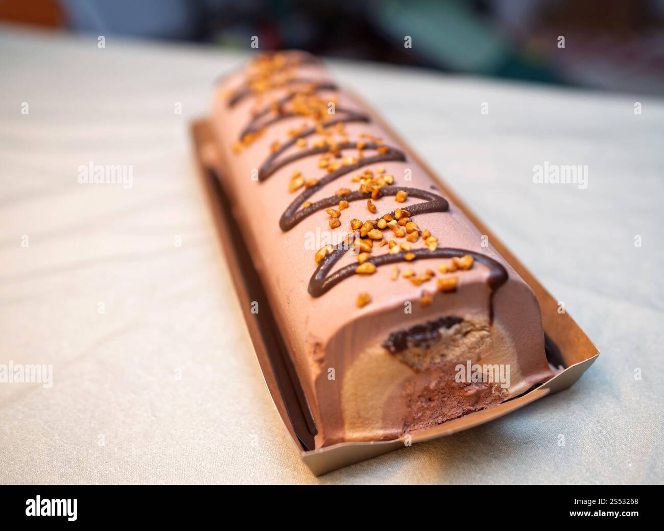 A chocolate ice cream log garnished with chocolate drizzle and crunchy ...