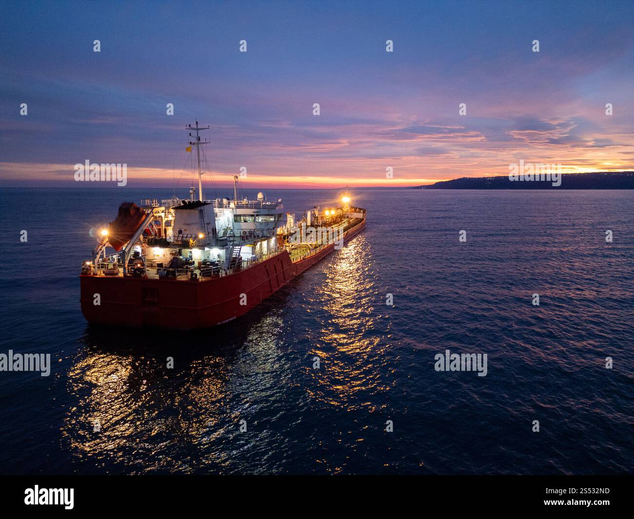 Aerial view of a brightly lit tanker ship on the sea during dusk ...