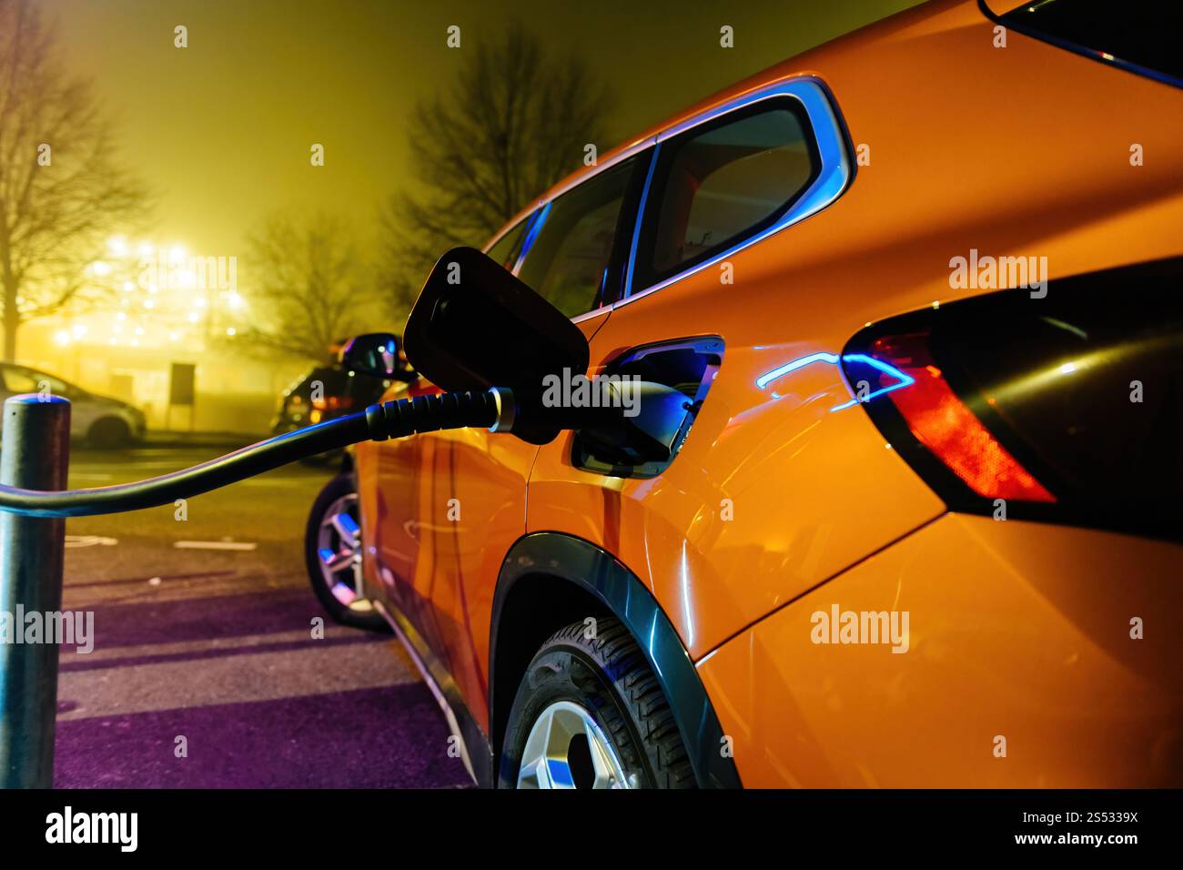 A close-up of an orange electric vehicle being charged at a public ...
