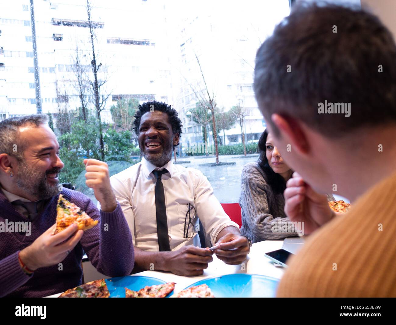 Colleagues Laughing Over Pizza in a Bright Office Setting Stock Photo - Alamy