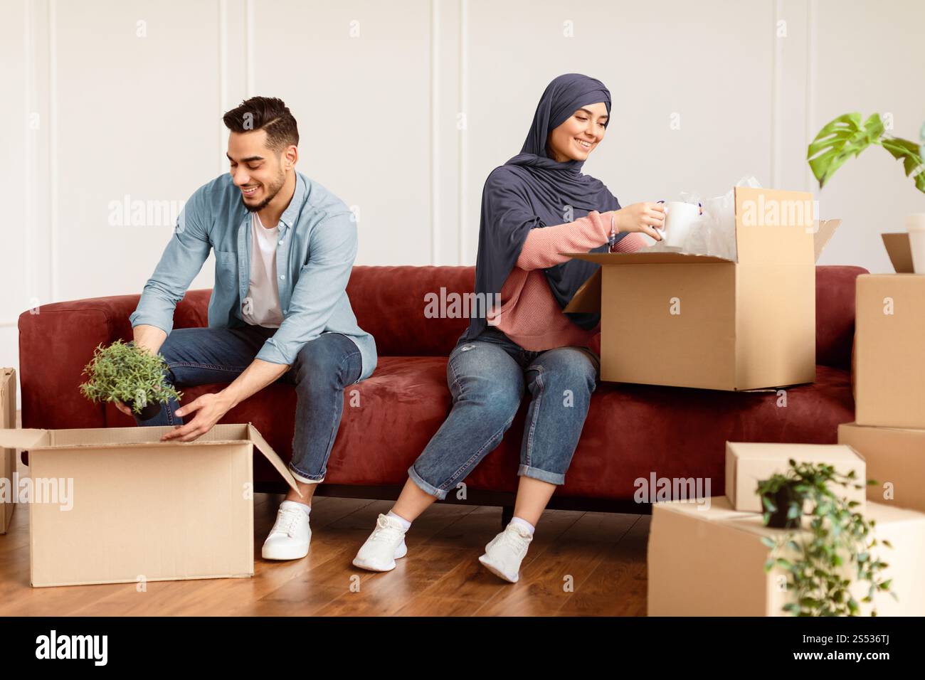 Happy man and woman in hijab packing or unpacking boxes Stock Photo - Alamy