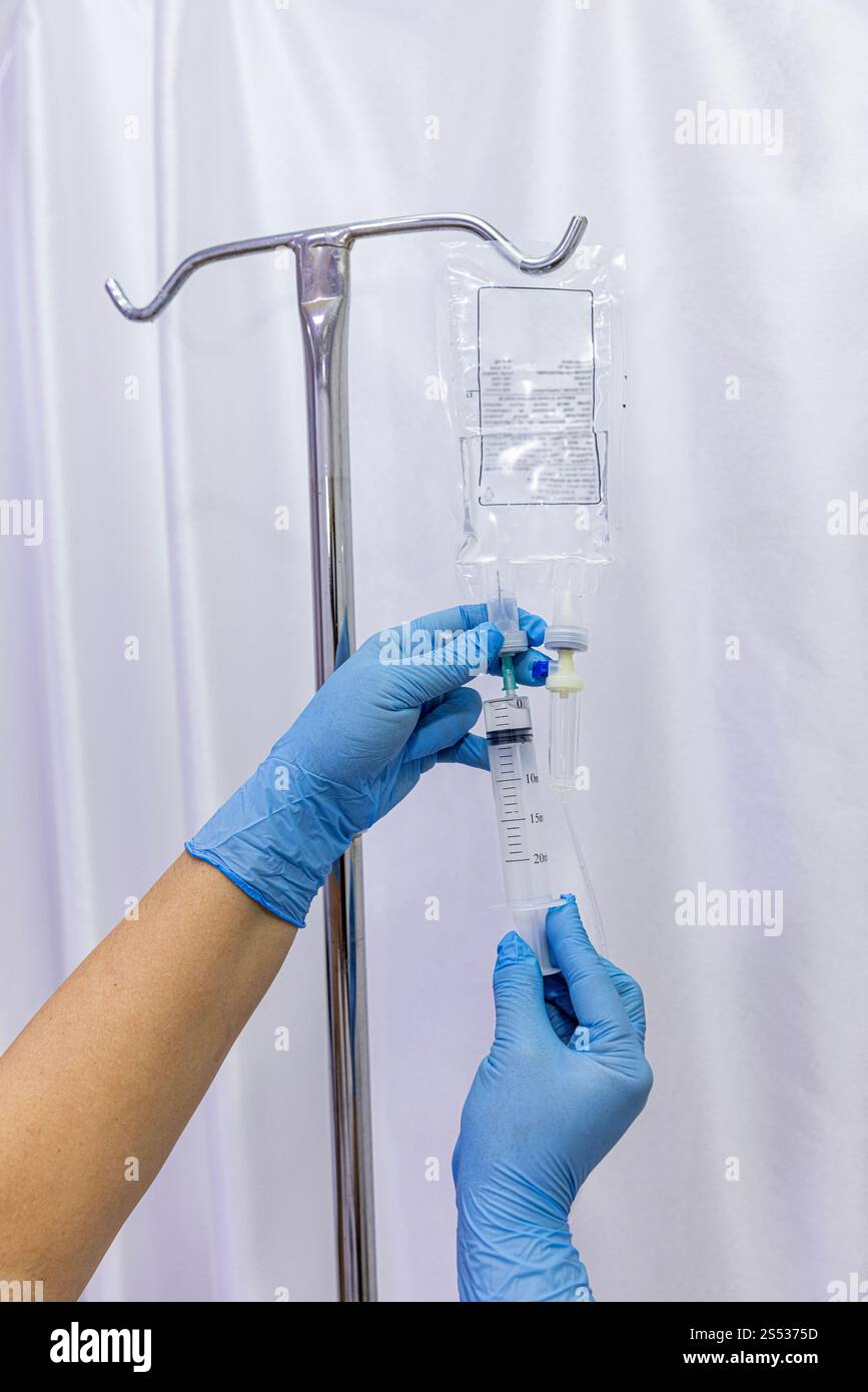 An unrecognizable doctor or nurse sets up a serum for a patient in a ...