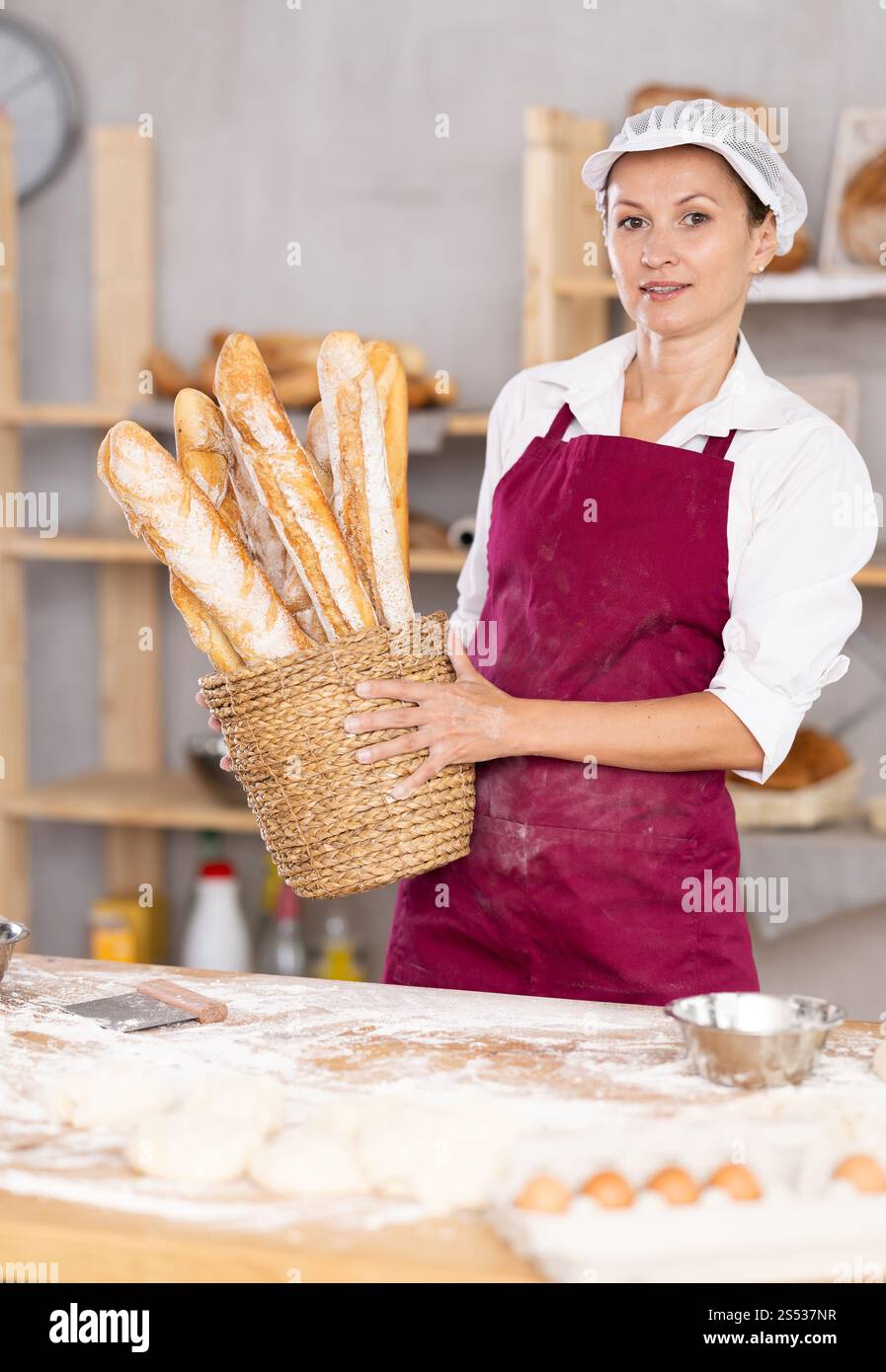 Adult female baker with basket of baguettes Stock Photo - Alamy