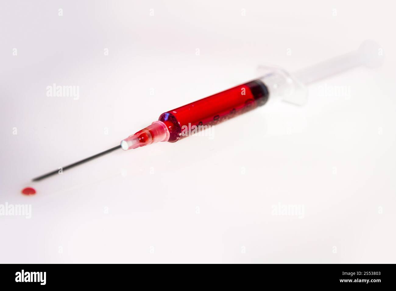 Syringe with blood closeup on white background. Syringe with blood on ...