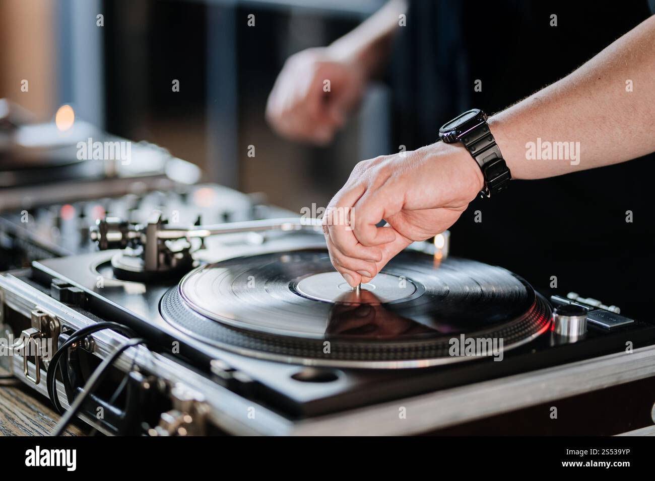 DJ mixing vinyl records on a turntable, creating an energetic vibe for ...