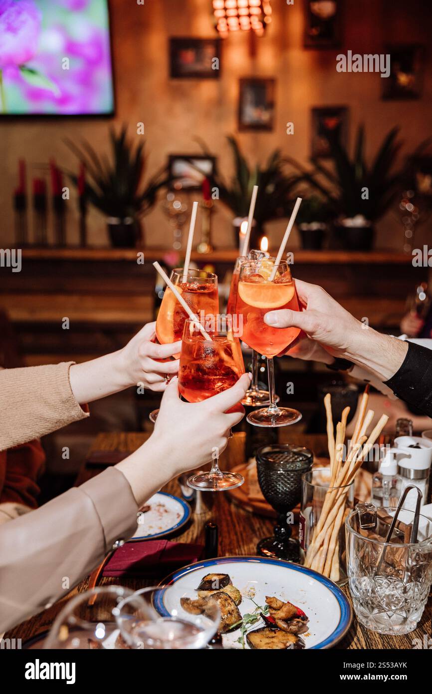 Celebration with Aperol spritz toasts, cozy dinner party vibes in a ...