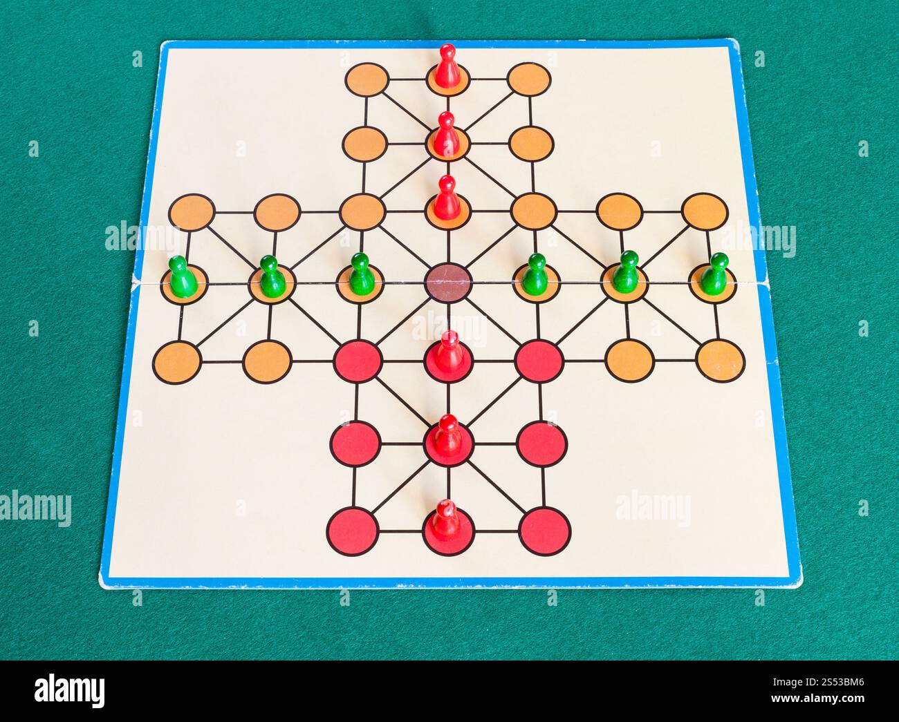 setup of cross solitaire board game on green baize table. The first ...