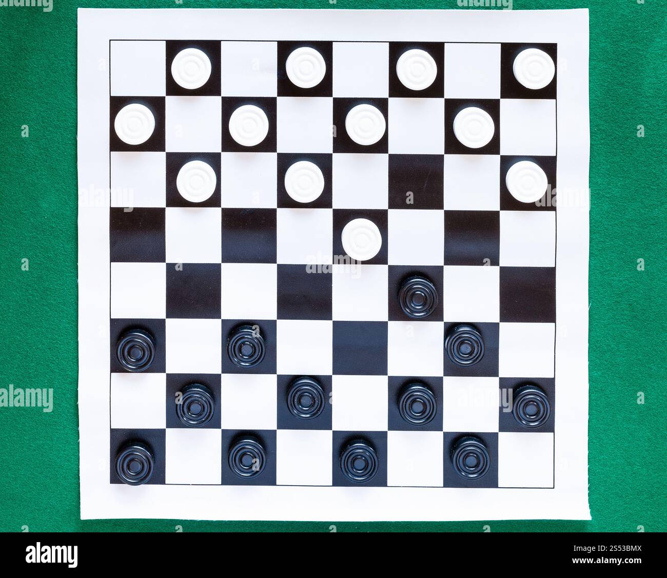 top view of checkers on black and white checkered sheet board on green ...