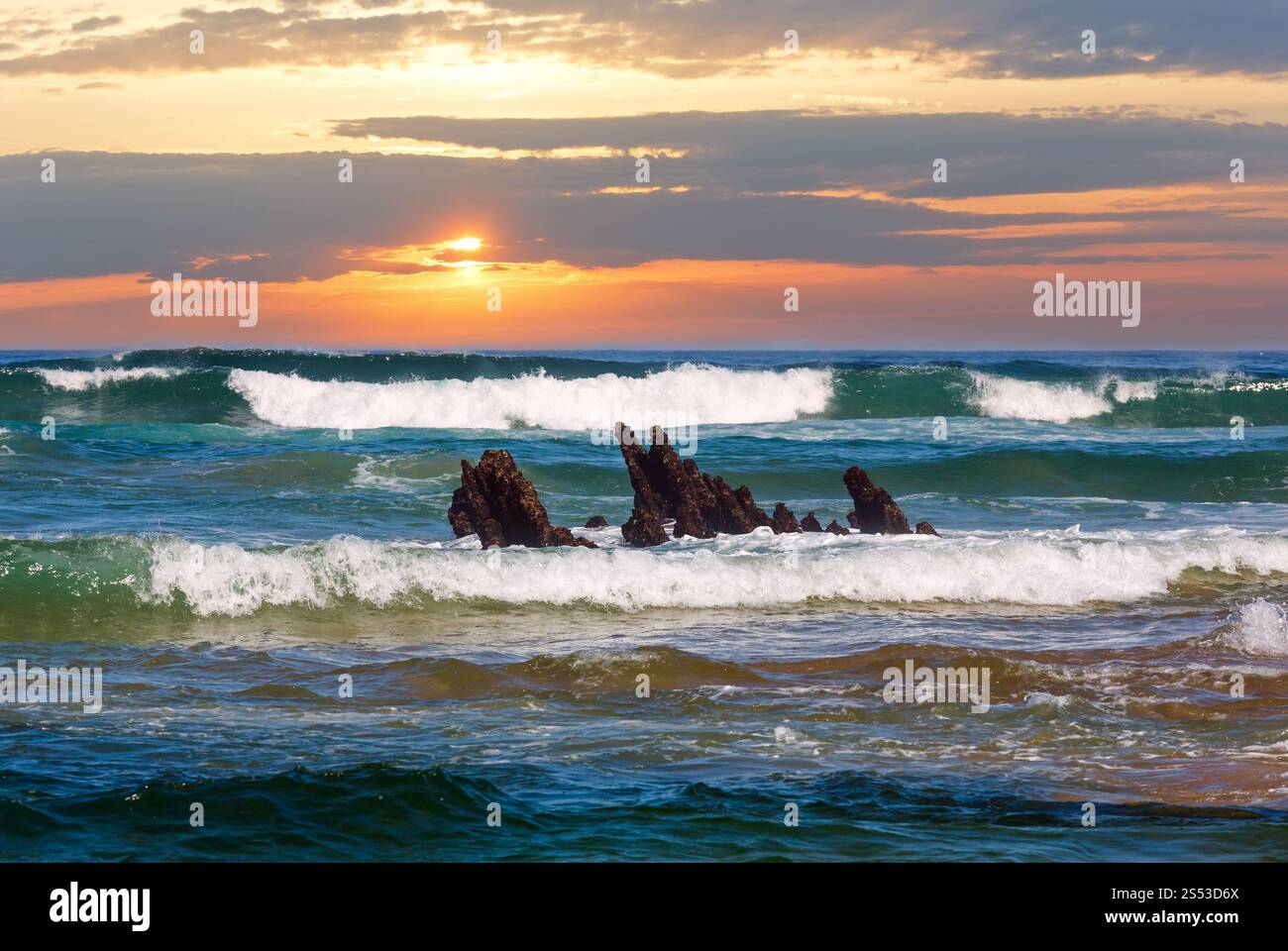 Sea surf waves and small rocks in center. Evening sunset seascape view ...