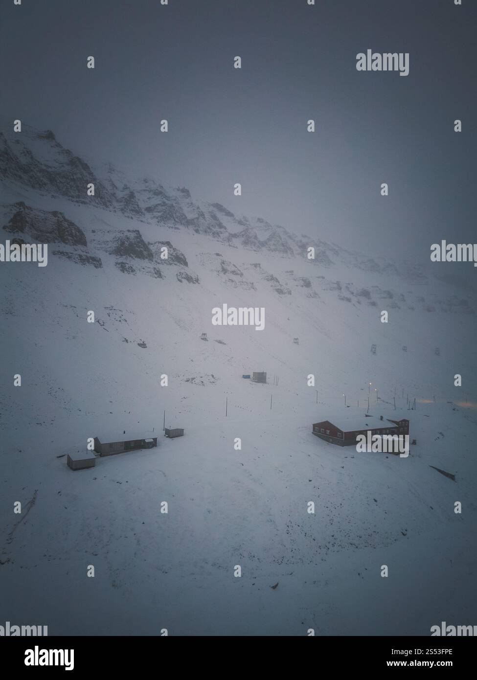 Aerial view of snowy buildings under mountain in Longyearbyen, Svalbard ...