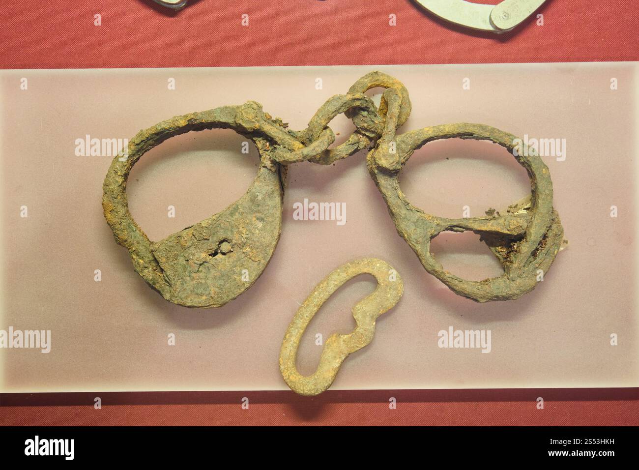 A display of old, rusty, green patina handcuffs, clamps. At the ...