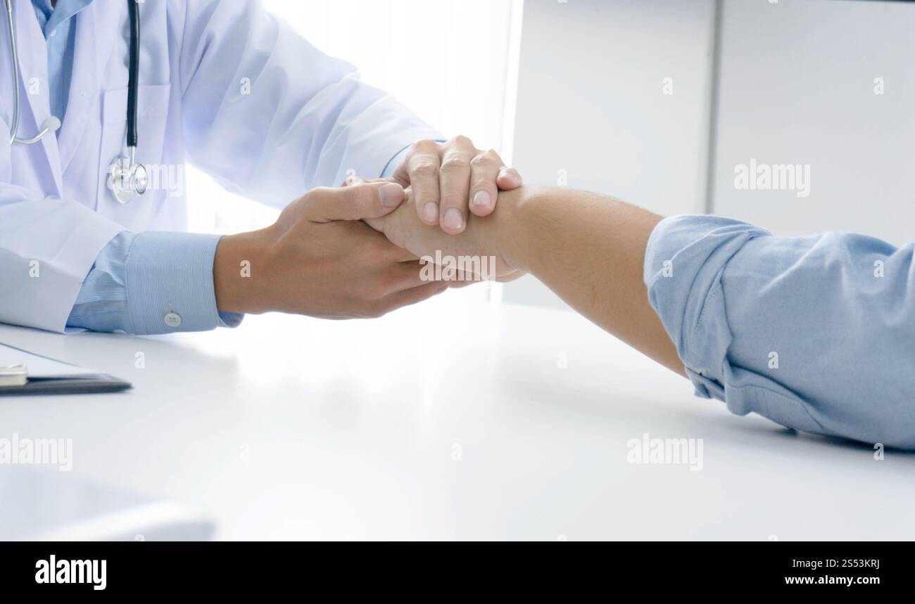 Doctor holding patients hand, and reassuring his male patient helping ...