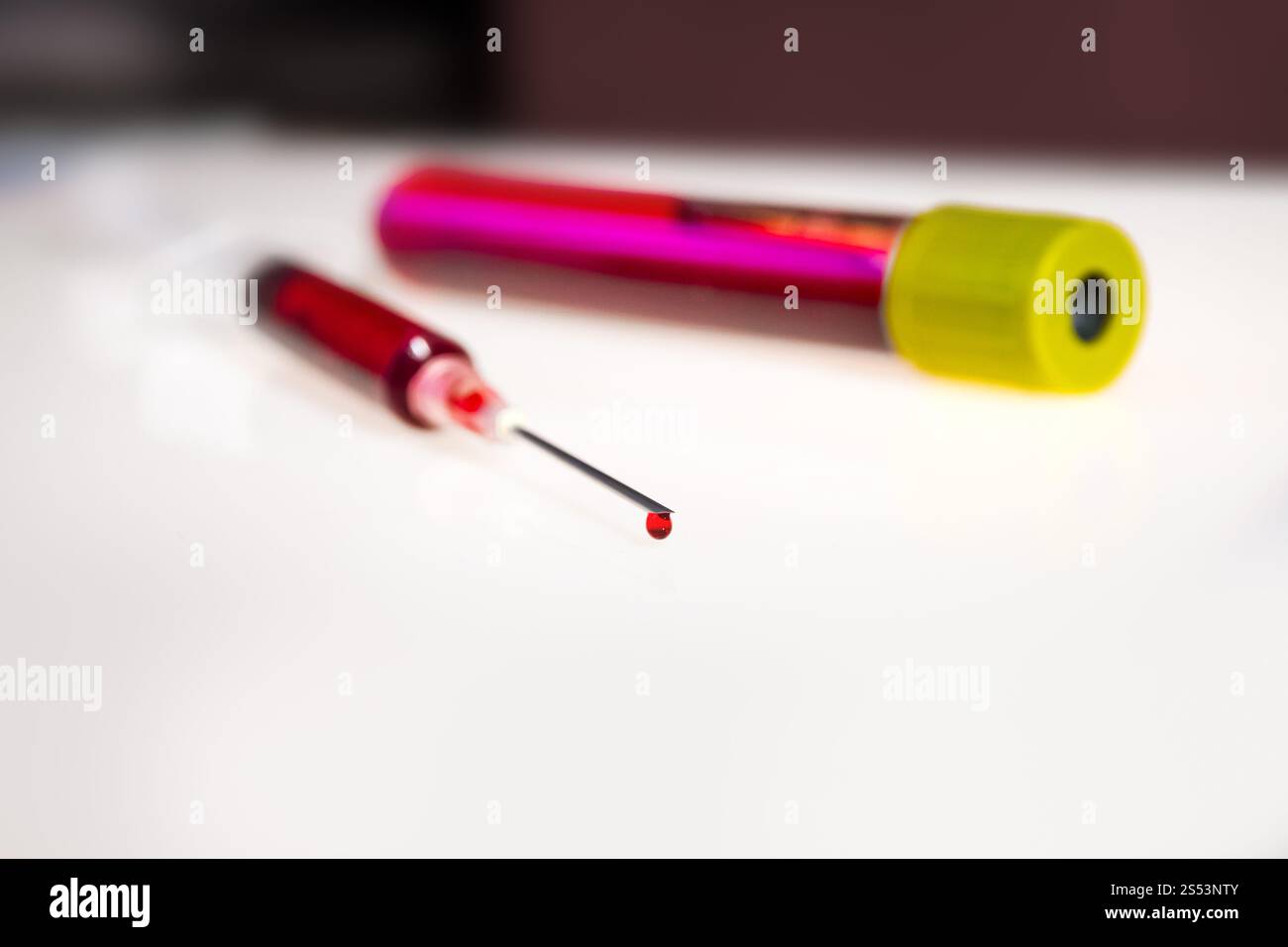 Syringe needle and test tube with blood macro view. Syringe needle and ...