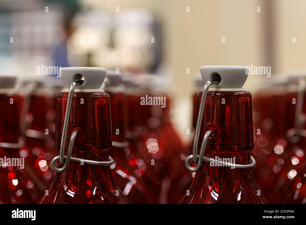 Close-up of the necks of rows of clear red bottles in an industrial ...