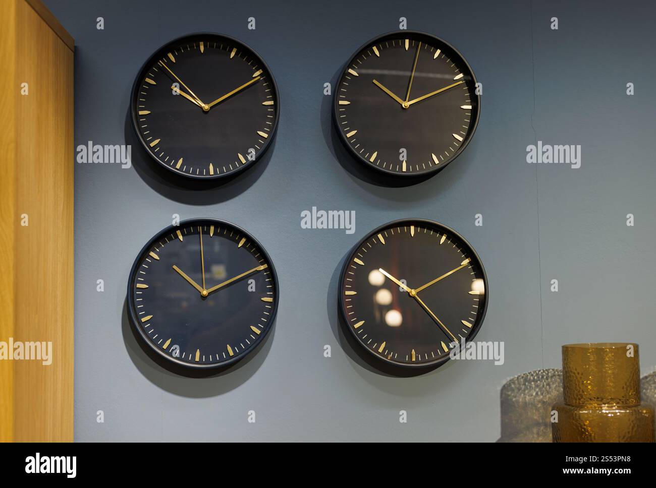 Multiple wall clocks displaying different times on a gray wall in a ...