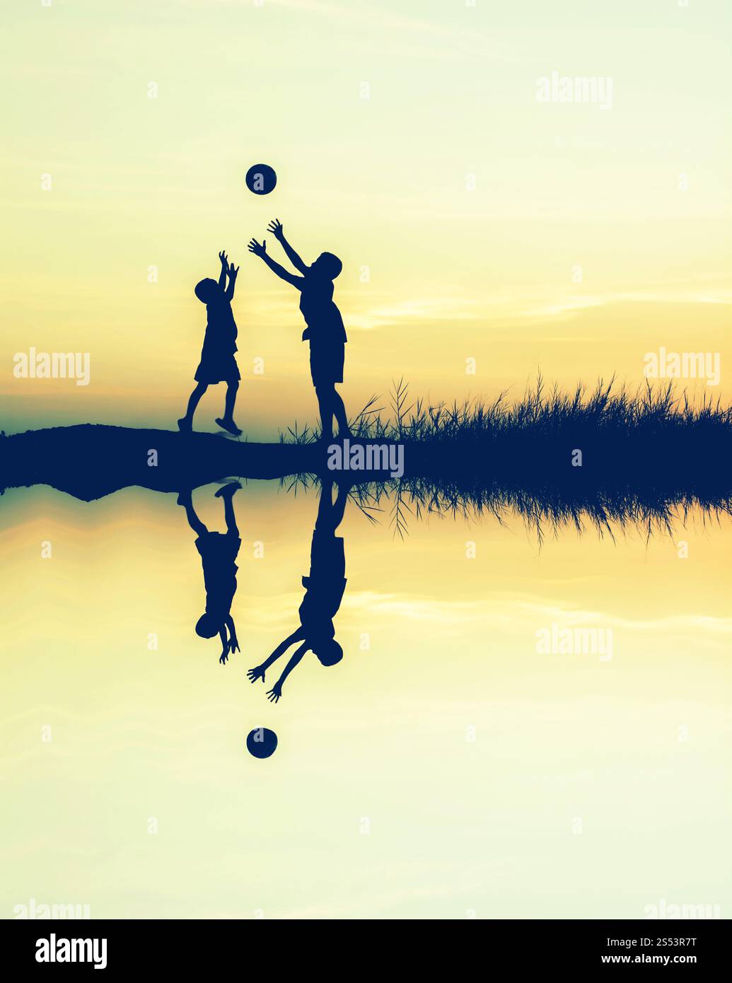 boys playing football at sunset with water reflection. silhouette ...