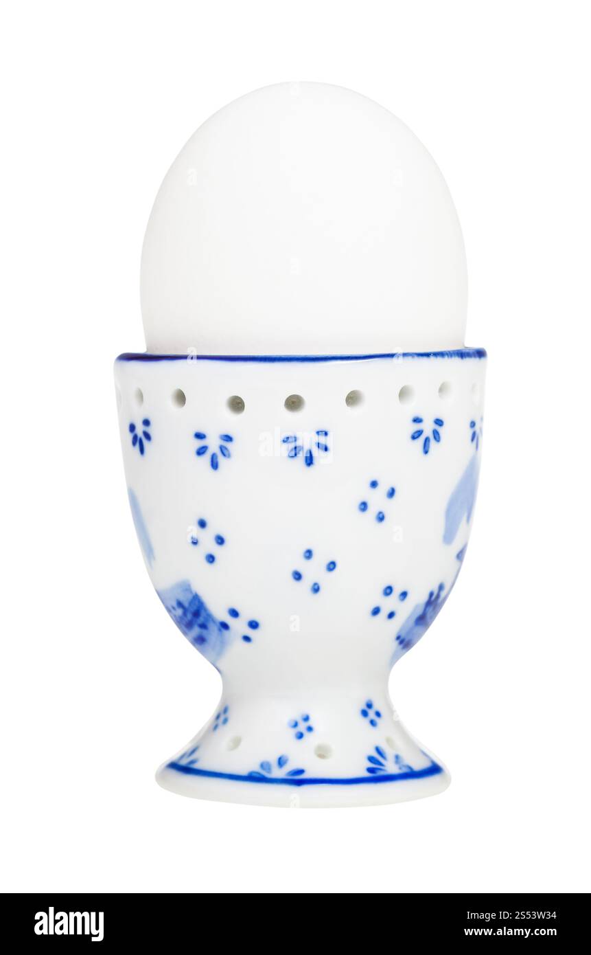 side view of white boiled egg in ceramic egg cup with a blunt end up ...