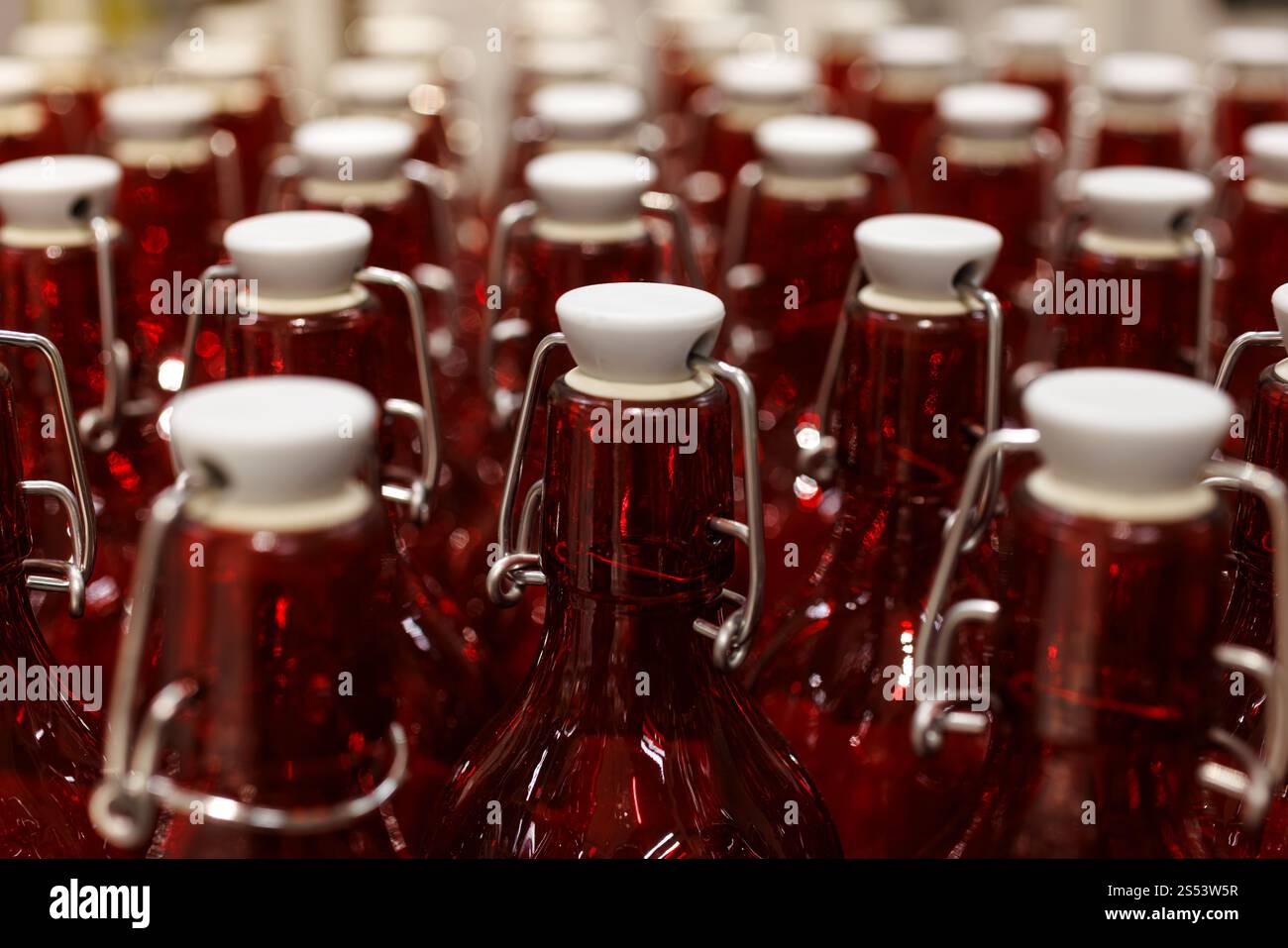 Close-up of the necks of rows of clear red bottles in an industrial ...