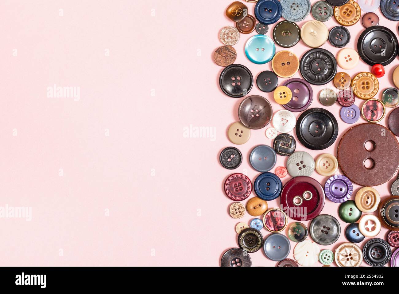 top view of many various buttons on pink background with blank ...