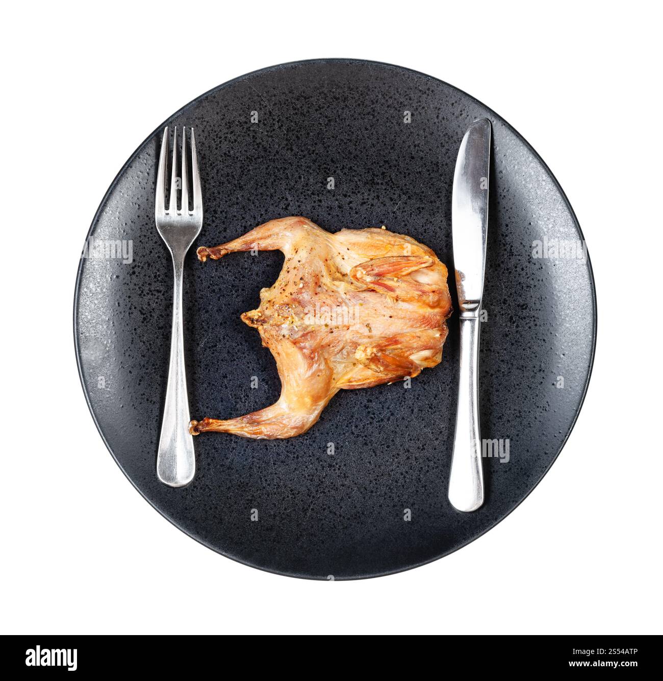 top view of roasted whole flattened quail with fork and knife on black ...
