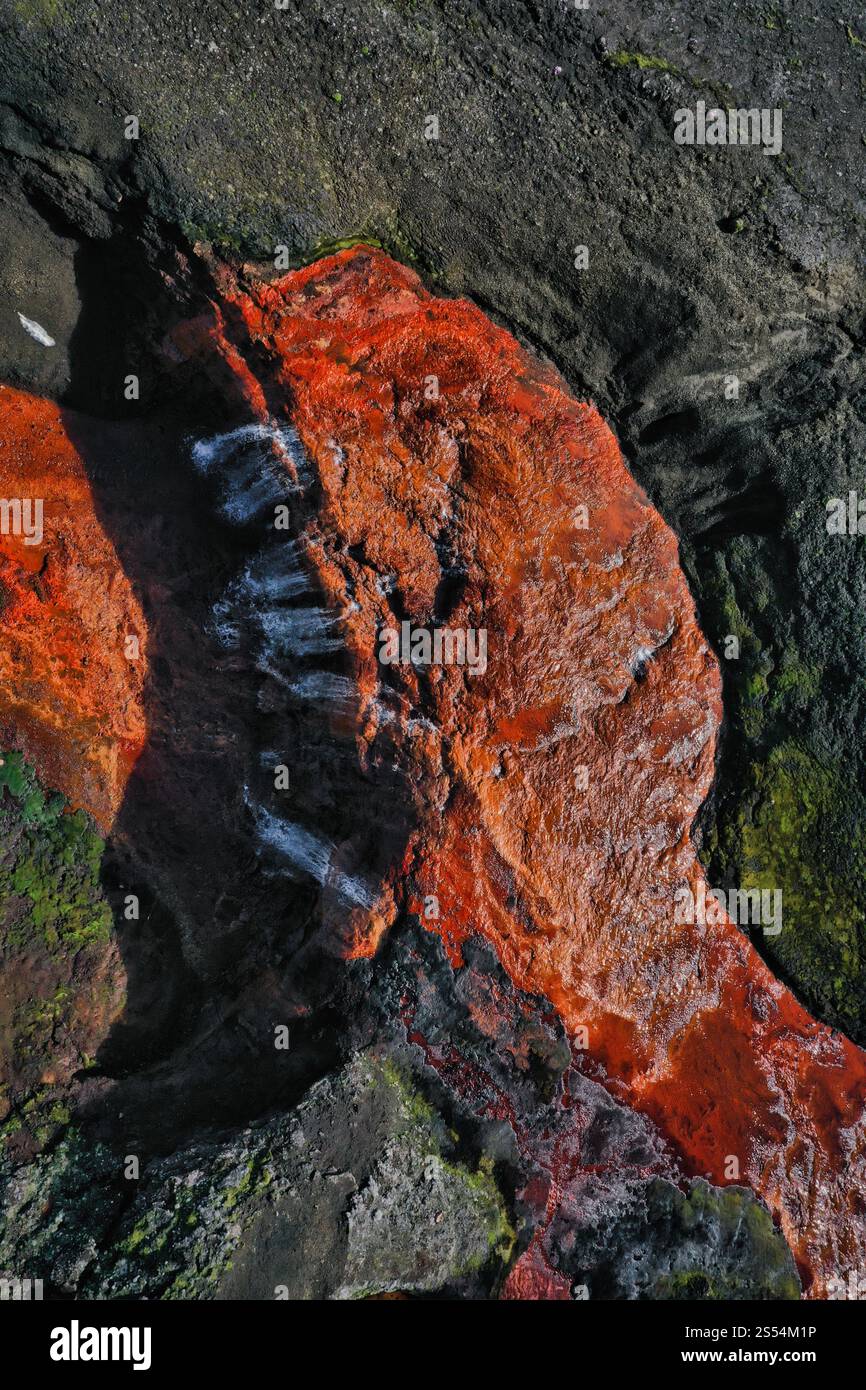 Aerial view of a red-orange iron-rich river winding through Iceland’s ...