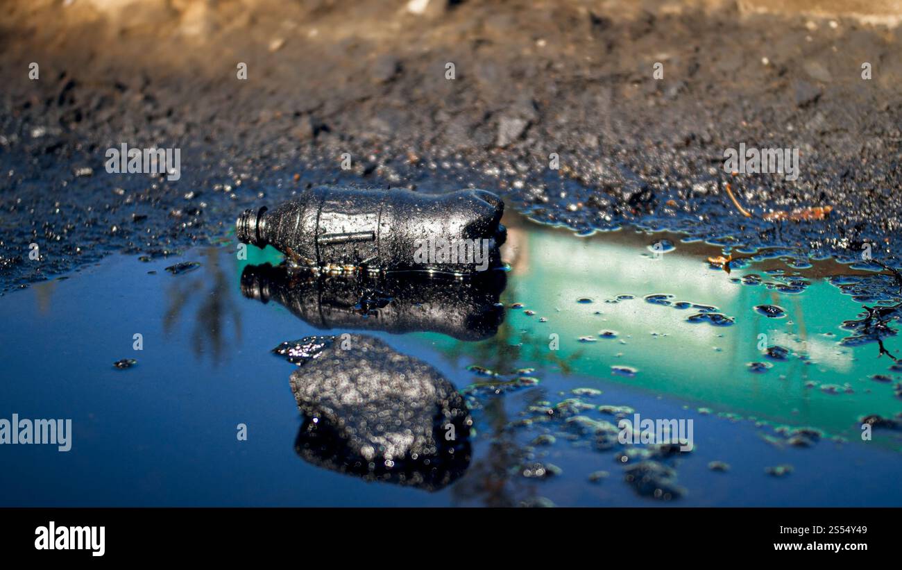CLoseup image of plastic bottle lying on dirty ground polluted with oil ...