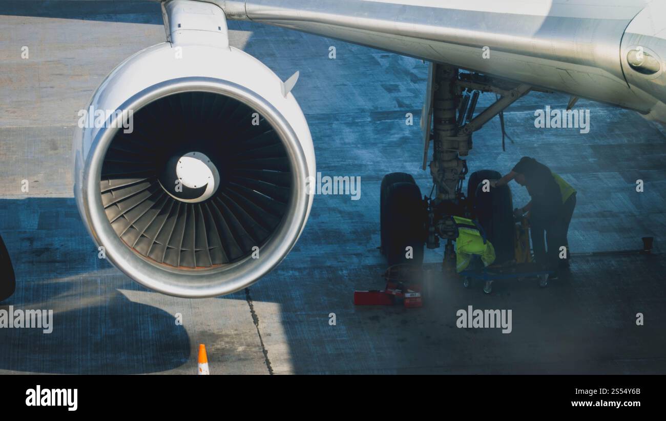 Ground service crew repairing and preparing airplane for flight in ...
