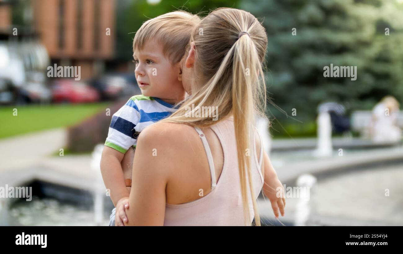 Portrait of young mother hugging and caressing her crying little child ...