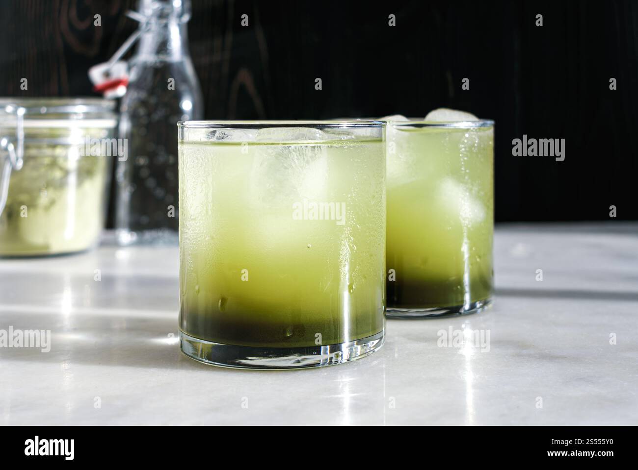 Two Glasses of Matca Soda with Ice Cubes: Sparkling water mixed with matcha simple syrup served ...