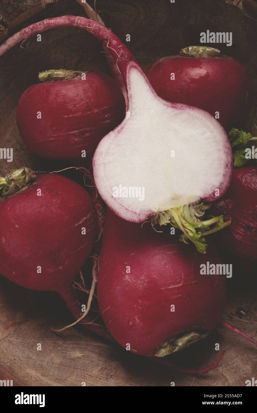 Bright red radishes lie in a rustic wooden bowl, highlighting their ...