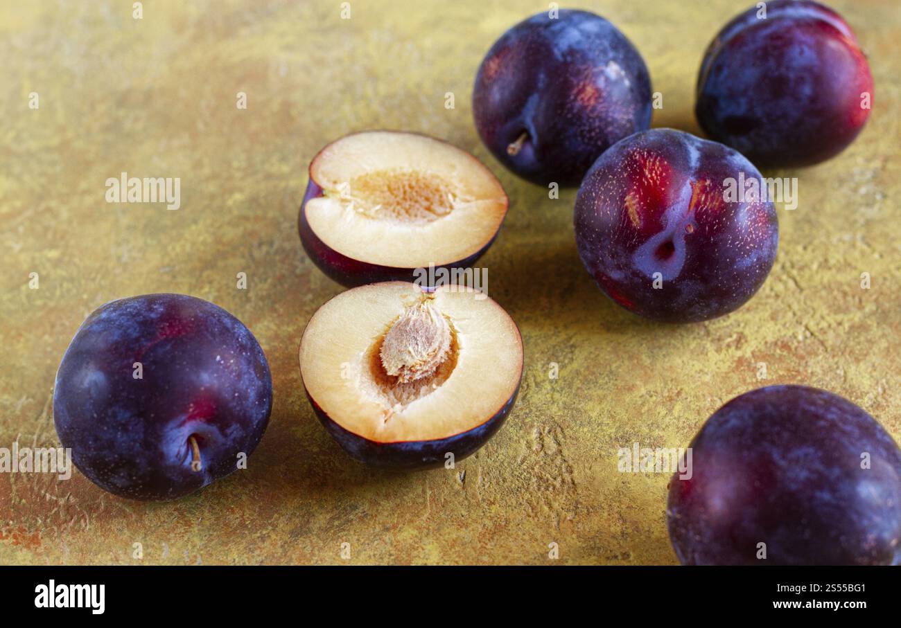 Plums scattered on the table, fresh, top view, yellow-orange background ...