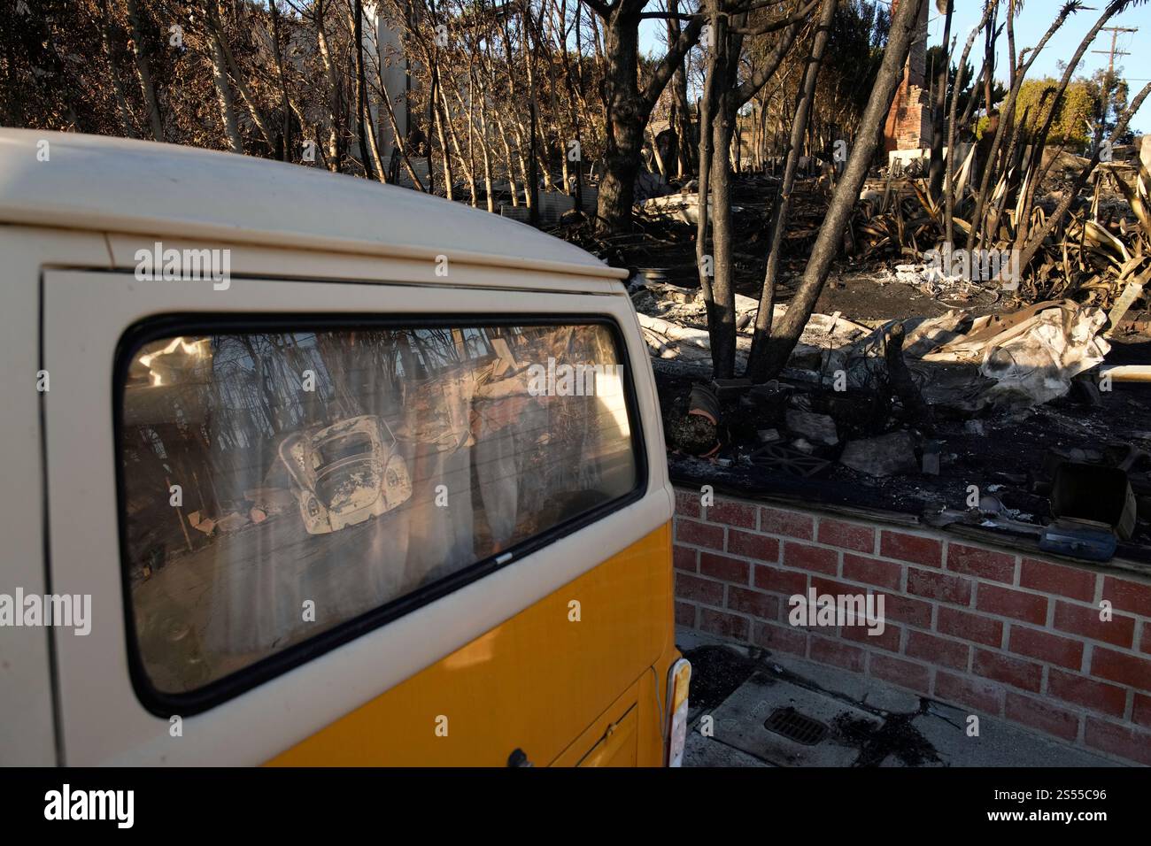 A destroyed Volkswagen Beetle is reflected in the back window of an ...