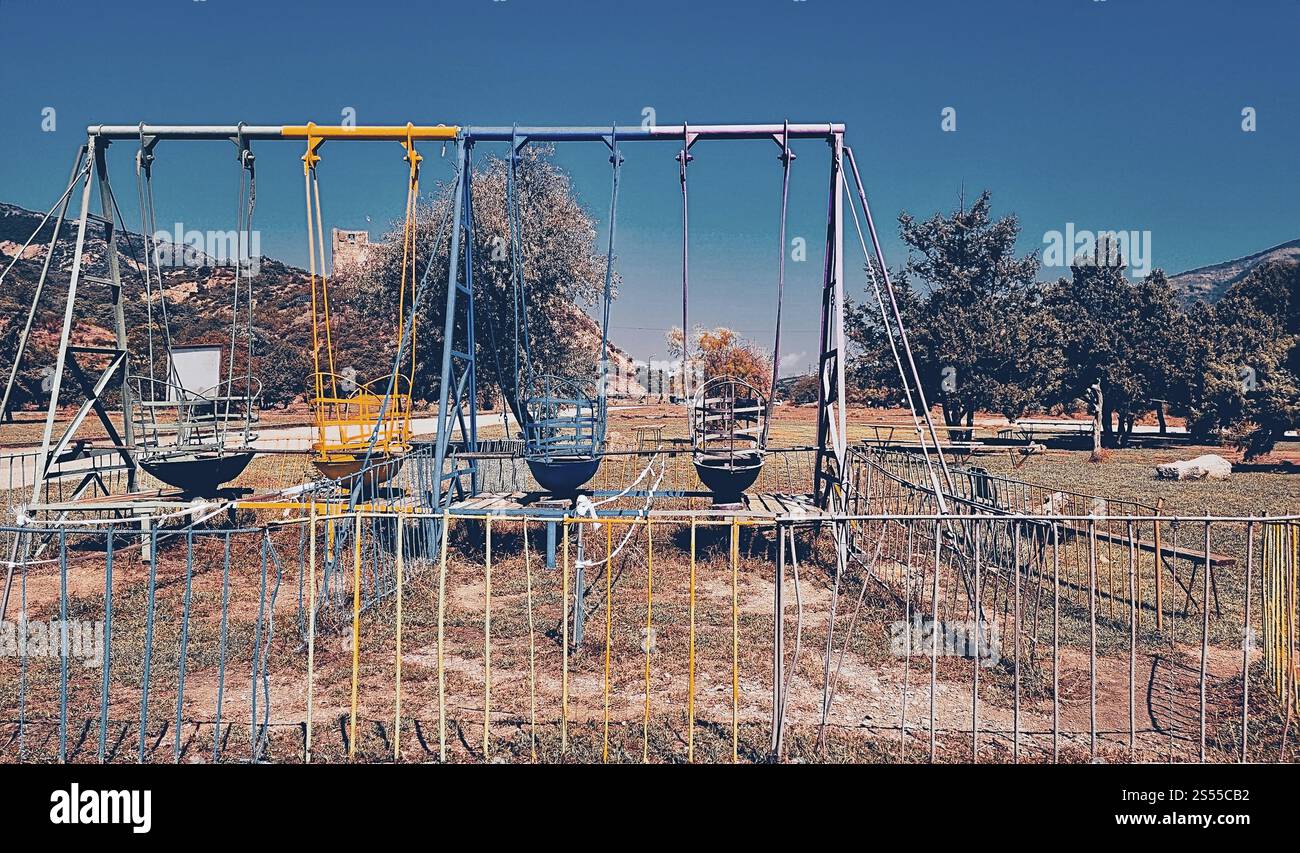 An old swing, on a quiet playground surrounded by green hills, on a ...