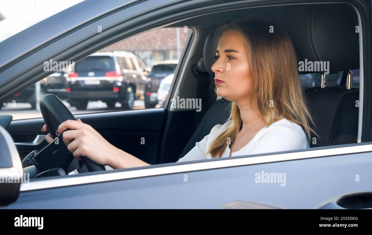 Portrait Through Open Car Window Of Young Concentrated Woman Driving A
