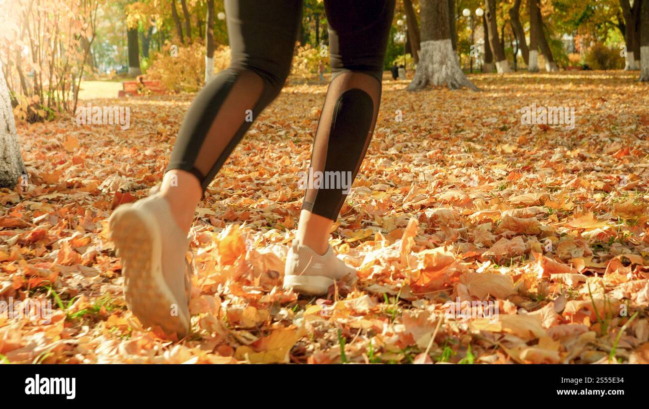 Closeup image of female feet running on fallen yellow tree leaves at ...