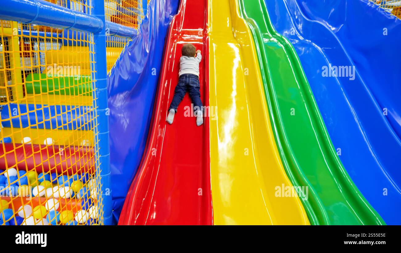 Little toddler boy sliding on colorful slide in ausement park at ...