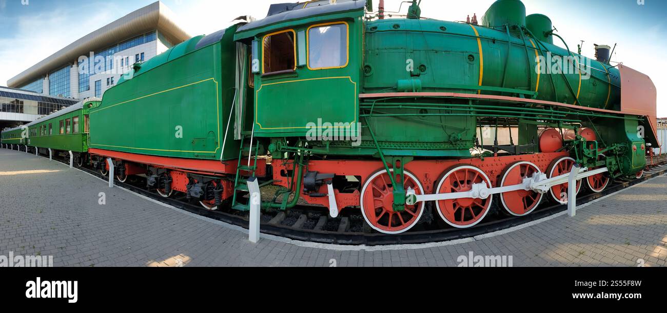 Panoramic photo of old steam train at mdoern railway station. Panoramic ...