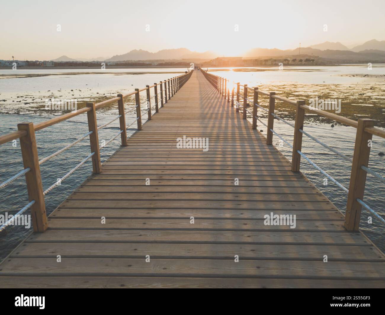 Beautiful view on sunset over ocean, mountain and long wooden pier ...