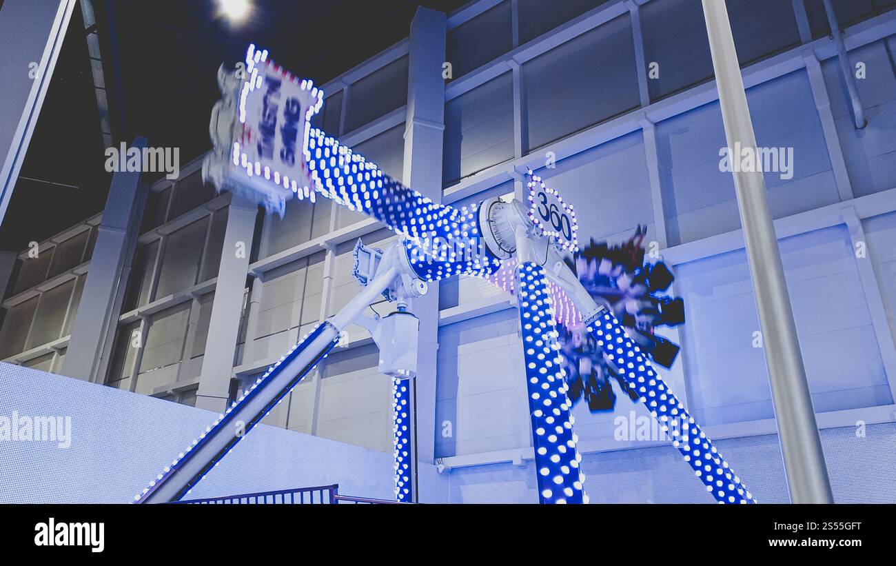 Toned photo of big swing that rotates upside down illuminated with lots ...