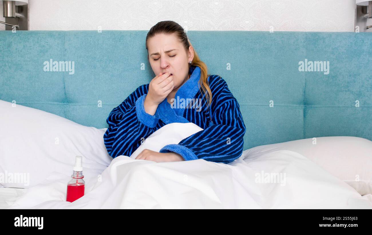 Portrait of young ill woman lying in bed and coughing. Portrait of ...