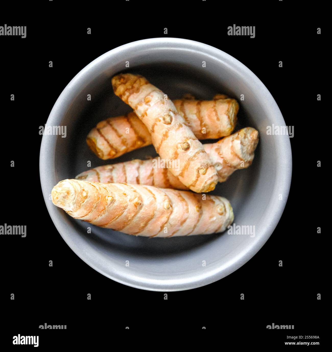 Turmeric root in a bowl isolated on black background. Top view ...