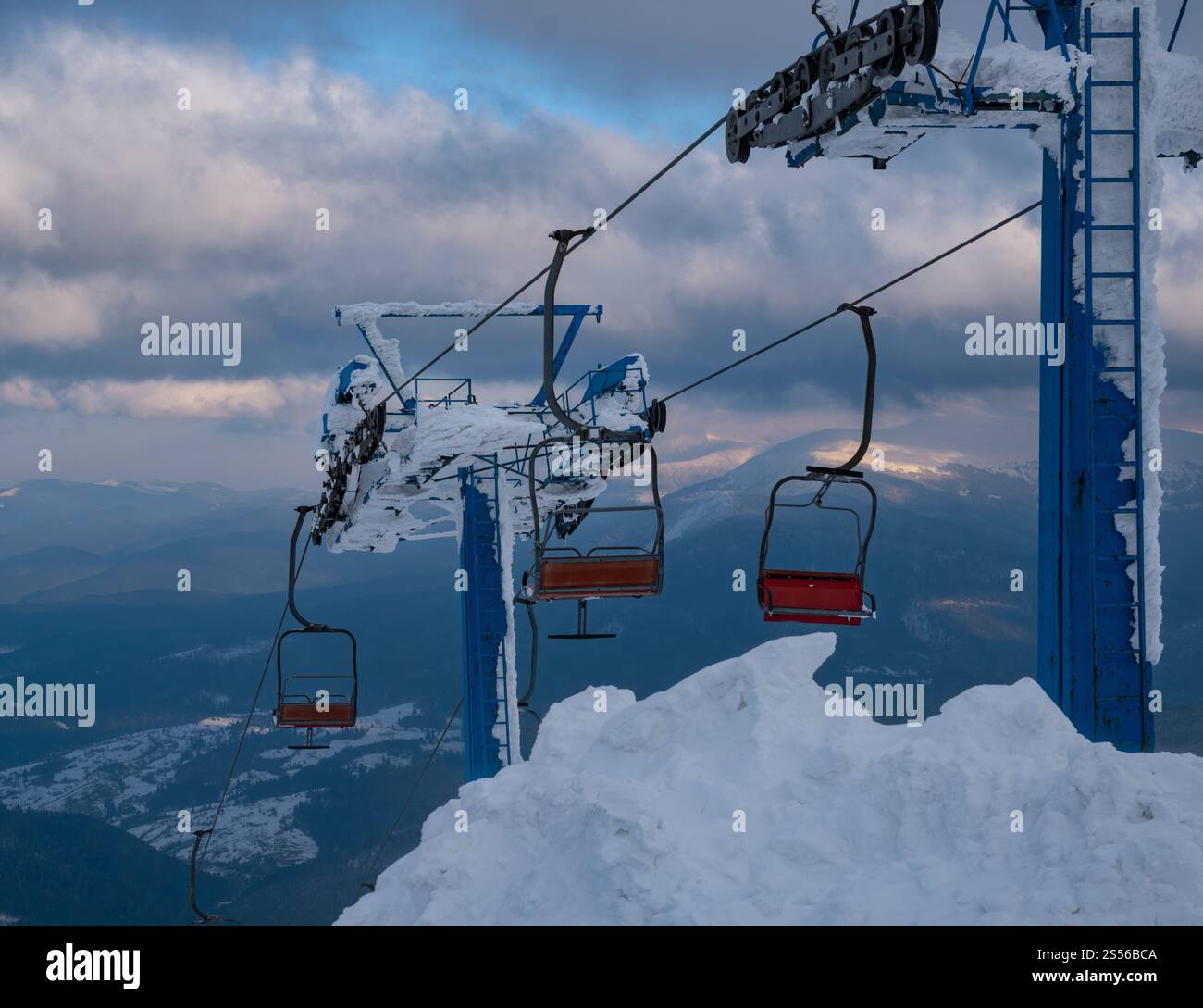 Alpine resort ski lift with seats going over the sunset mountain skiing ...