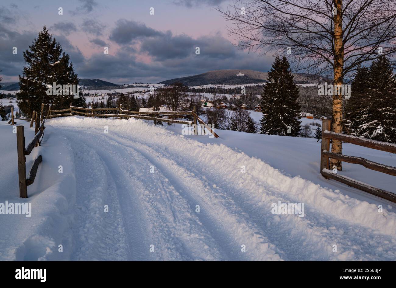 Snow drifts on road through twilight small and quiet winter alpine ...