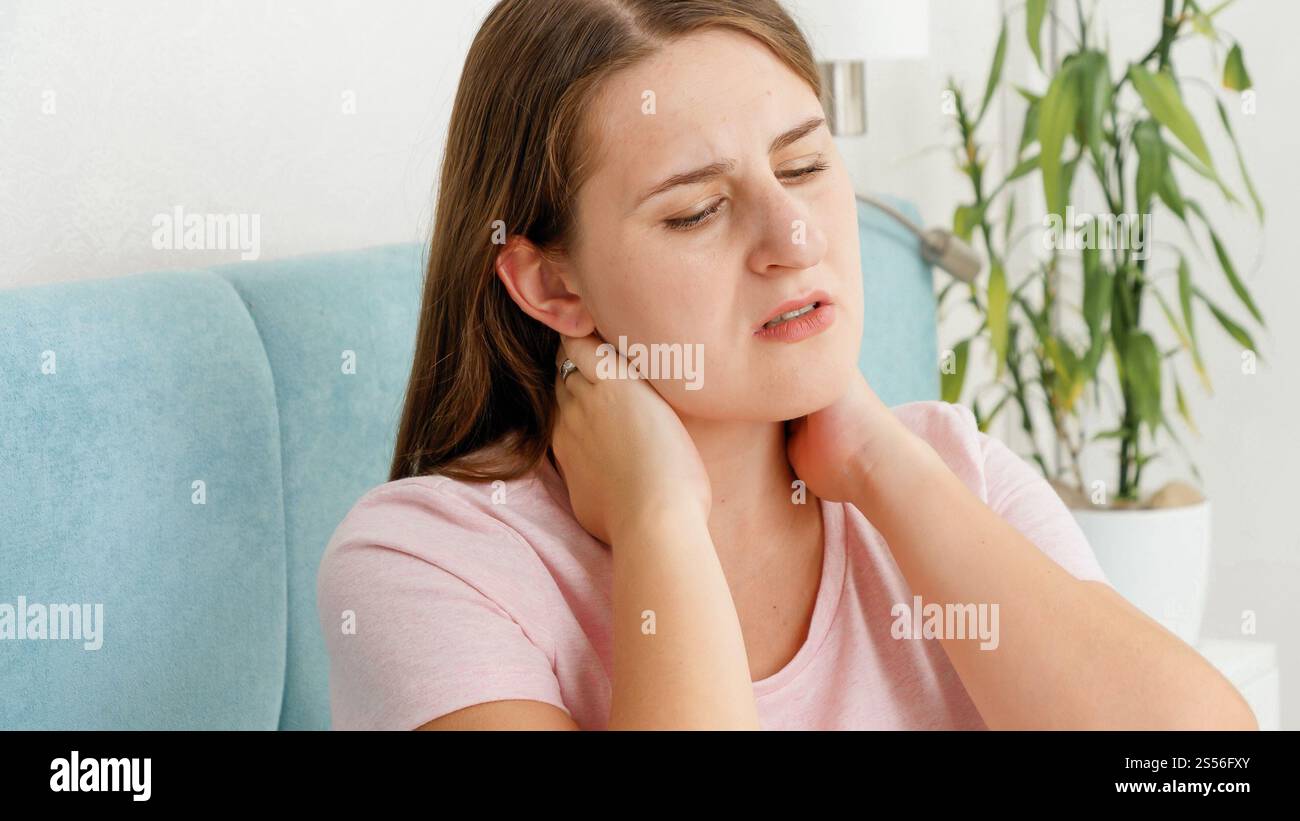 Young woman in pajamas suffering from pain in the neck and back after ...